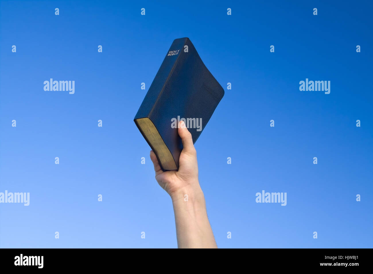 Hand holding Bible over blue sky Stock Photo - Alamy