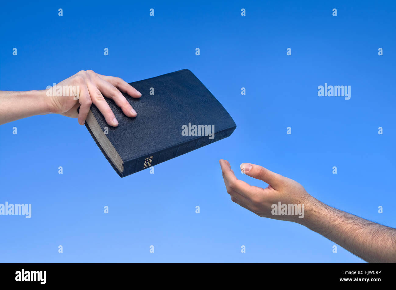 Hand giving the Bible to another person Stock Photo - Alamy