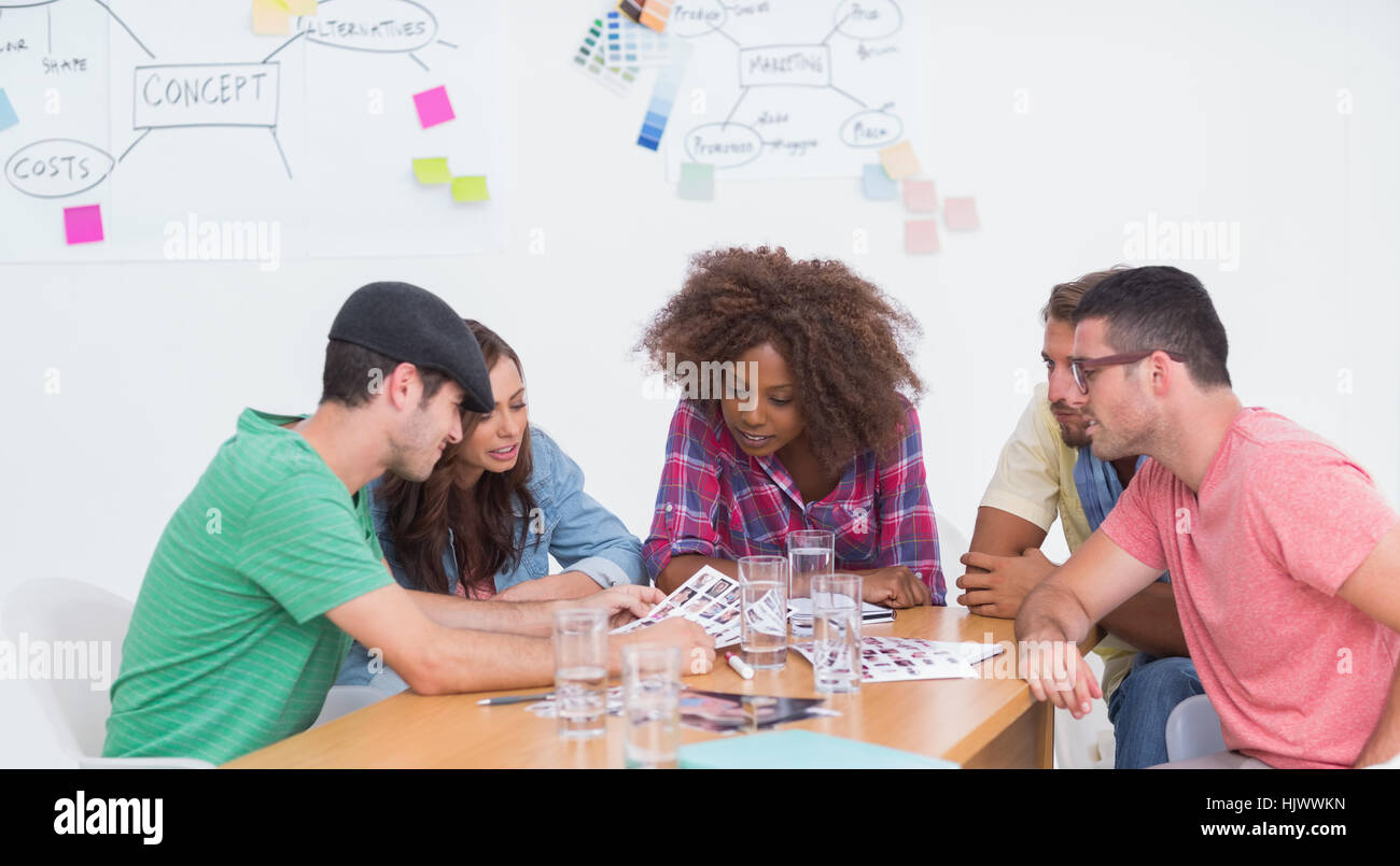 Creative team brainstorming over contact sheets in office with ...