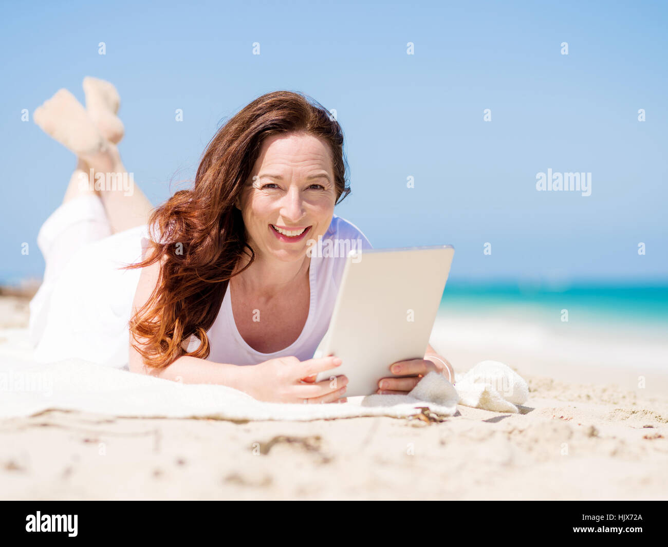 Woman in white clothes on the beach with tablet Stock Photo - Alamy
