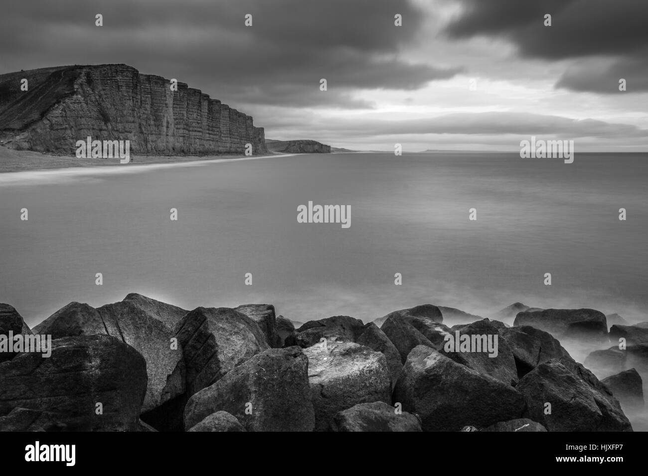 chiselled cliff worn away at West Bay with rocks in foreground Stock ...