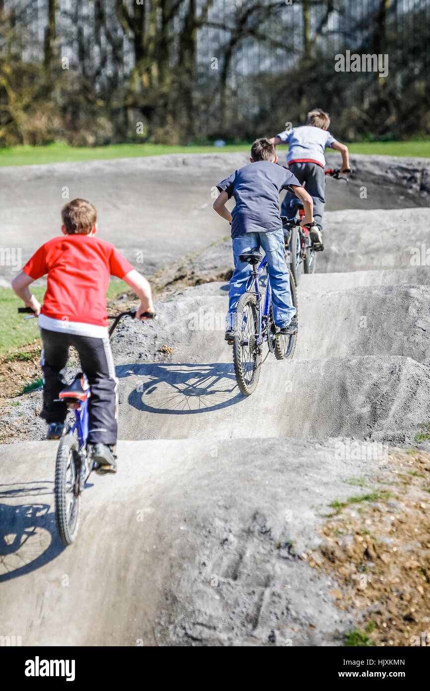 Three young boys on BMX bikes racing along a track Stock Photo - Alamy
