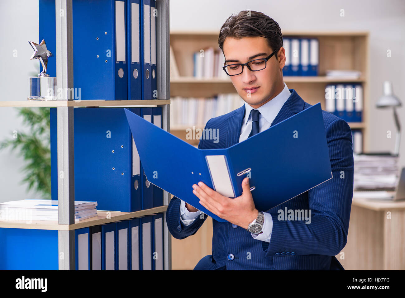 Young man standing next to the shelf with folders Stock Photo - Alamy