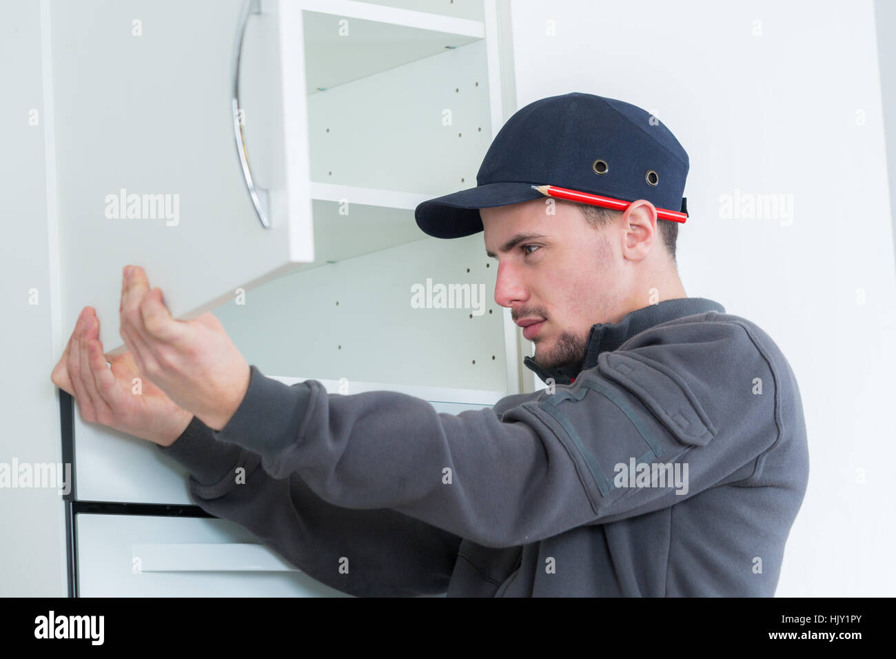 male carpenter installing cabinet in clients kitchen Stock Photo - Alamy