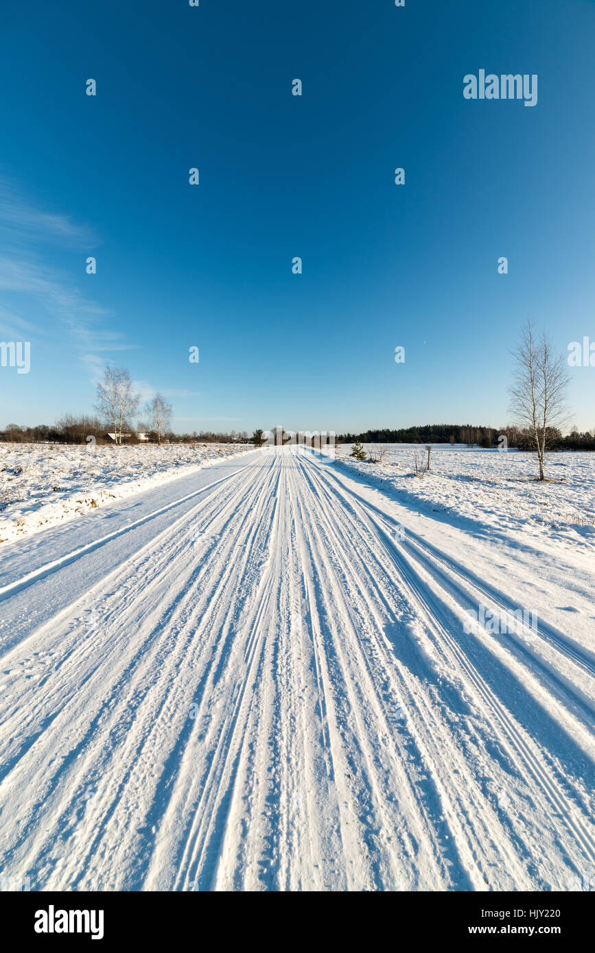snowy winter road with tire markings and blue sky Stock Photo - Alamy