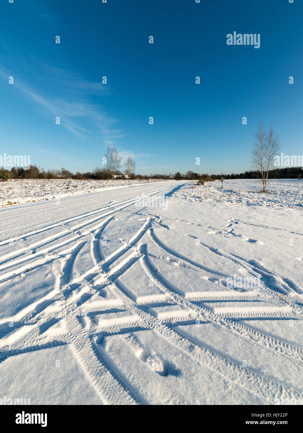 snowy winter road with tire markings and blue sky Stock Photo - Alamy