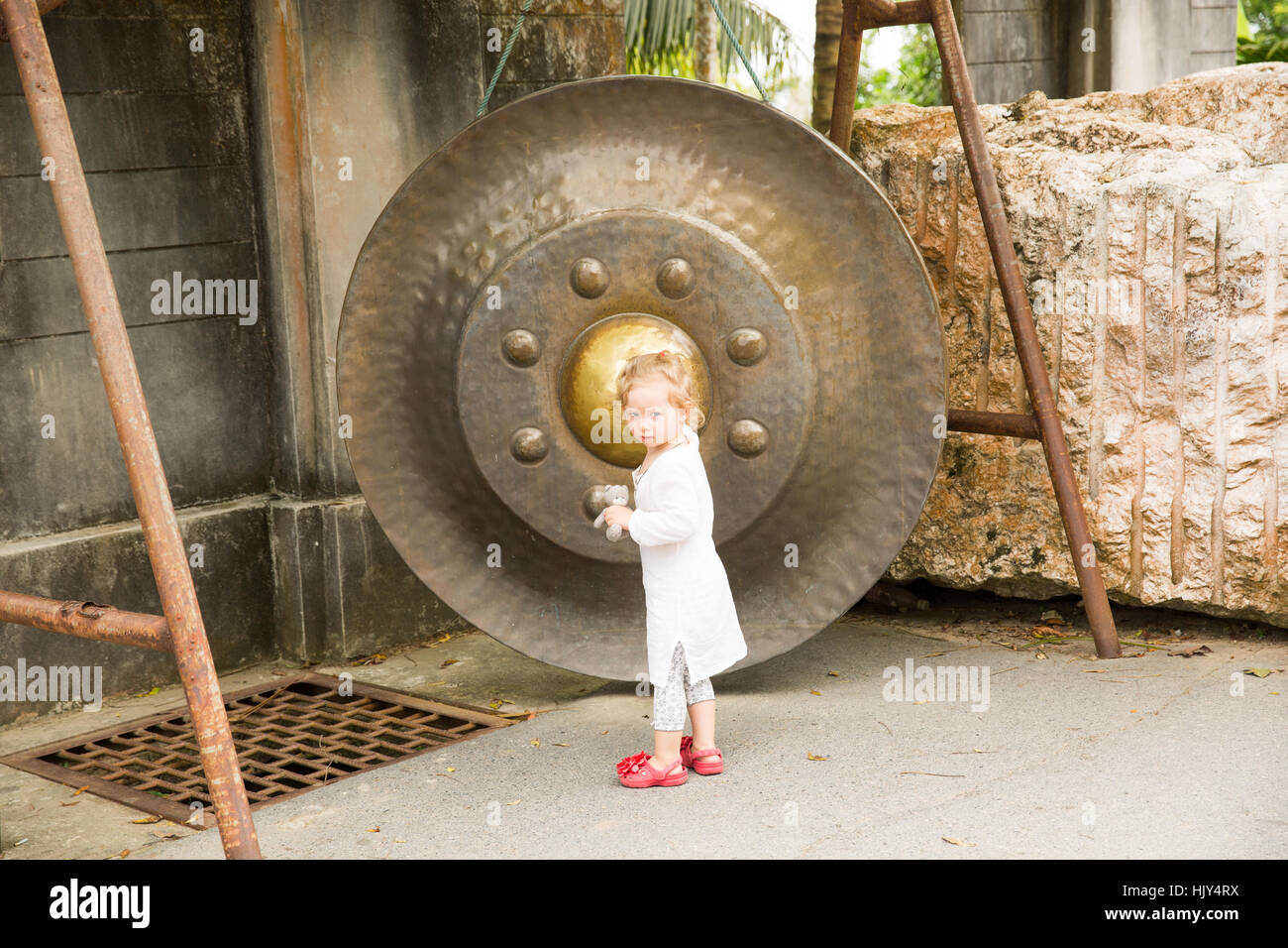 Child near Thai gong in Phuket. Tradition asian bell in Buddhism temple ...