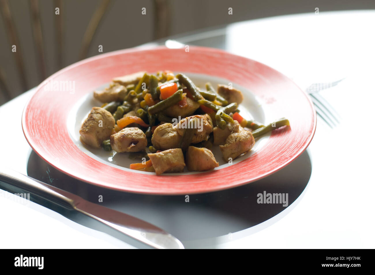 Chicken meat and vegetables on glass table served in red plate Stock ...
