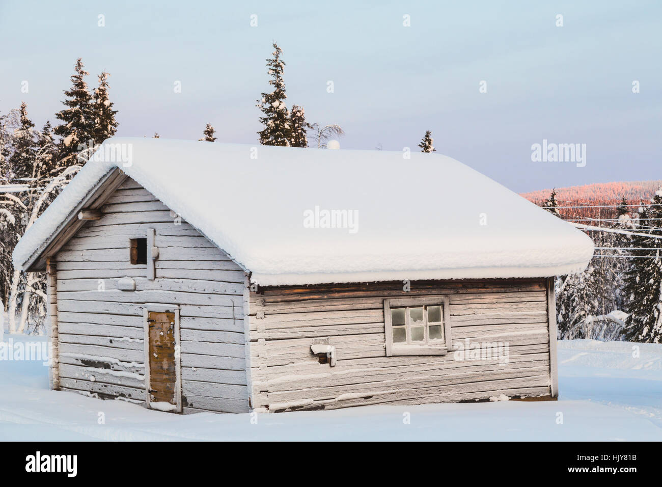 Old barn in winter with frosty window snow on the roff, snowy trees ...