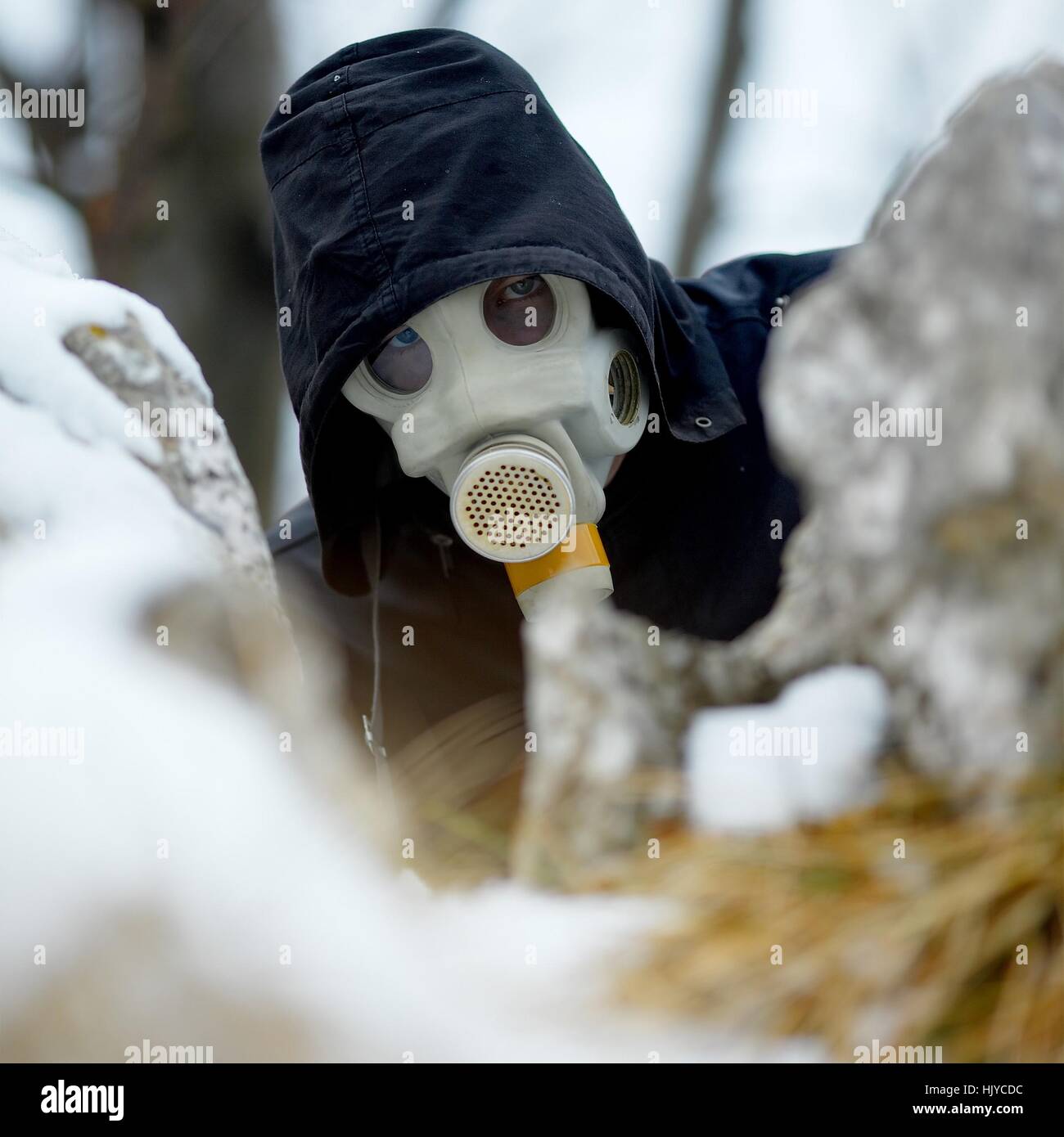 Man in gas mask hiding behind rocks Stock Photo - Alamy