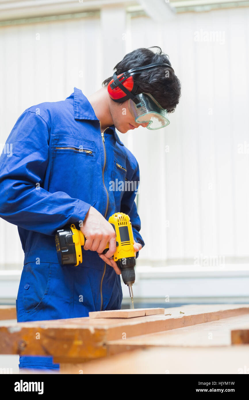 Student of a woodworking class learning to drill with nails in wooden ...