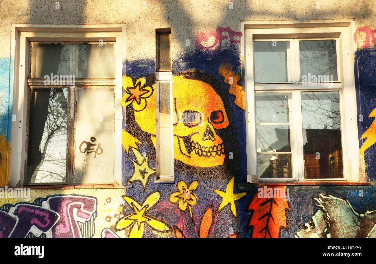 The picture of a yellow, smiling skull is seen on a wall between two ...