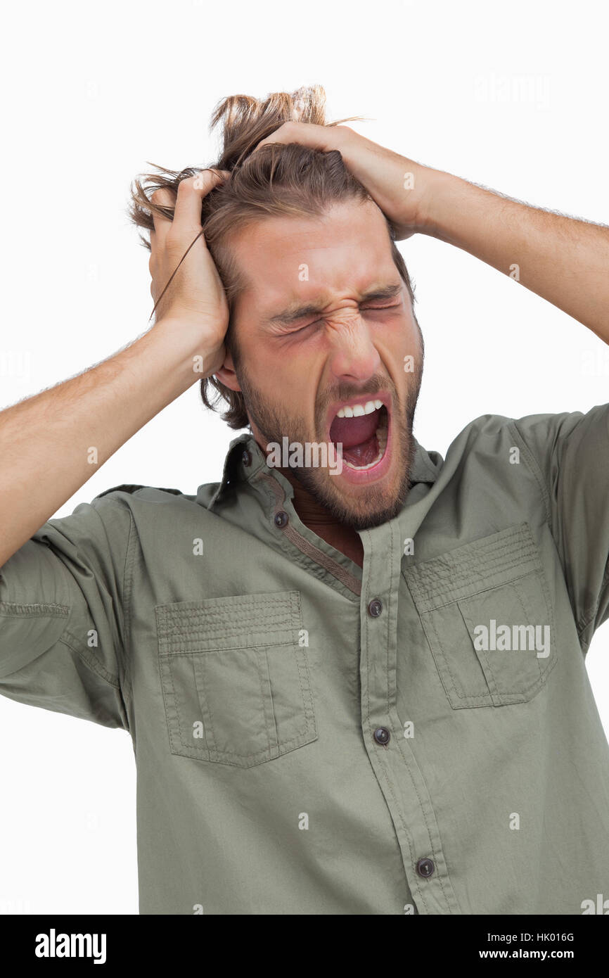 Tired man yawning and running fingers through hair on white background ...