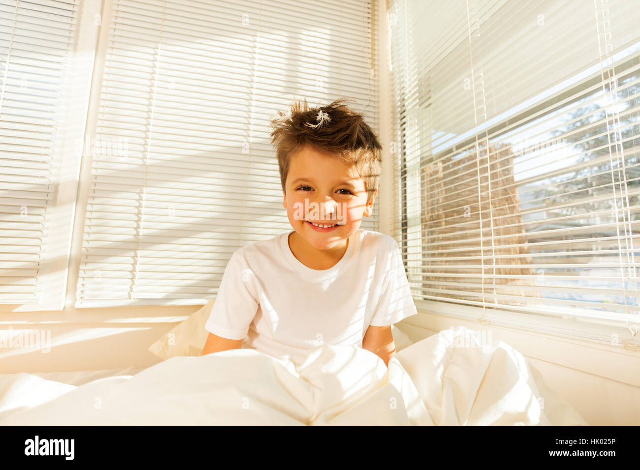Cute boy awaking in white bedroom full of sunlight Stock Photo - Alamy
