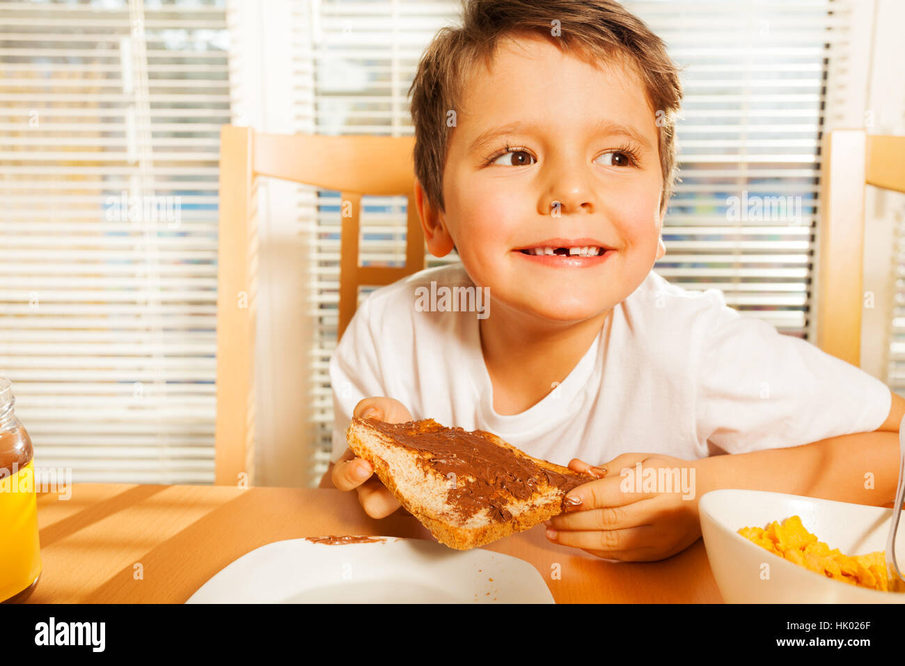 Happy kid boy holding toast with chocolate spread Stock Photo - Alamy