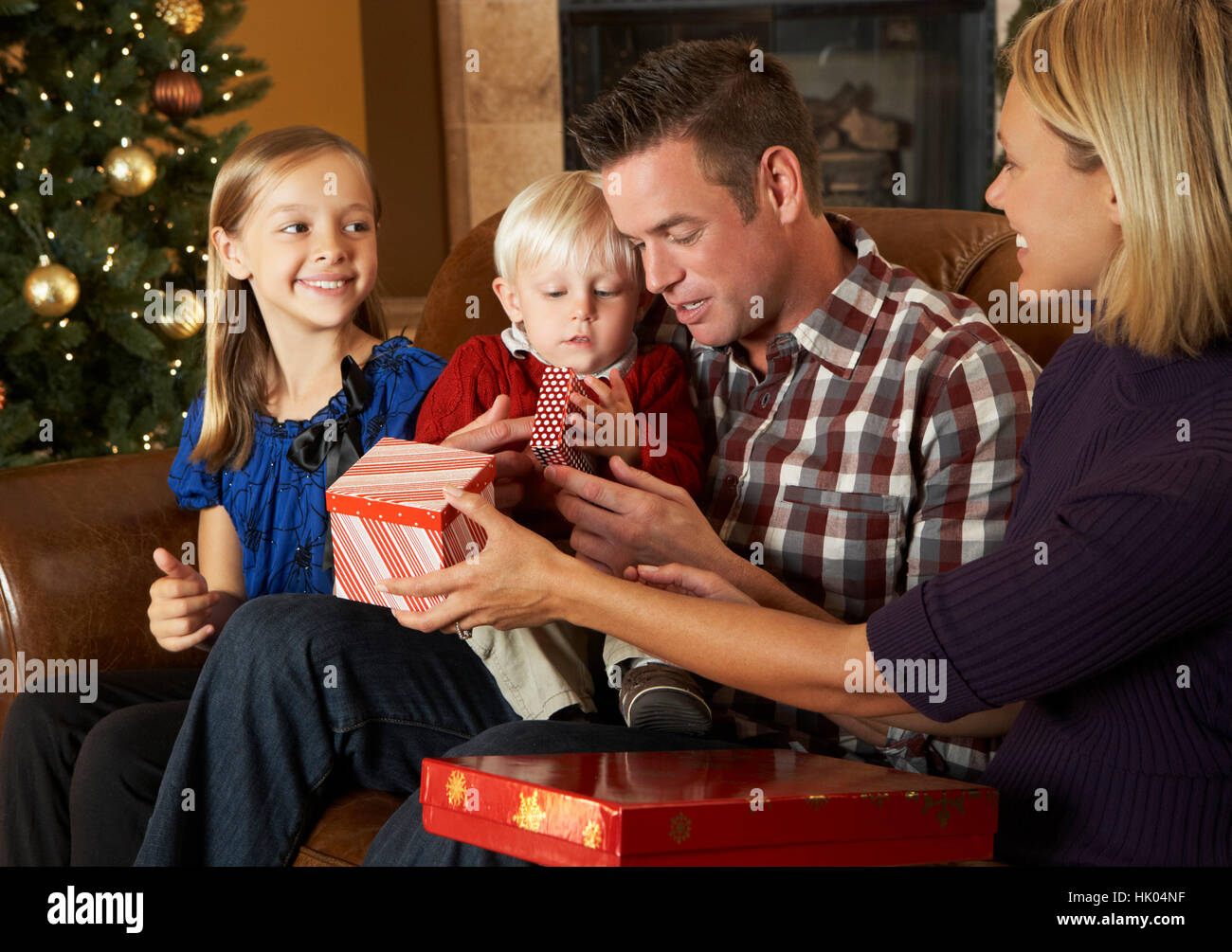 Family Opening Presents In Front Of Christmas Tree Stock Photo - Alamy