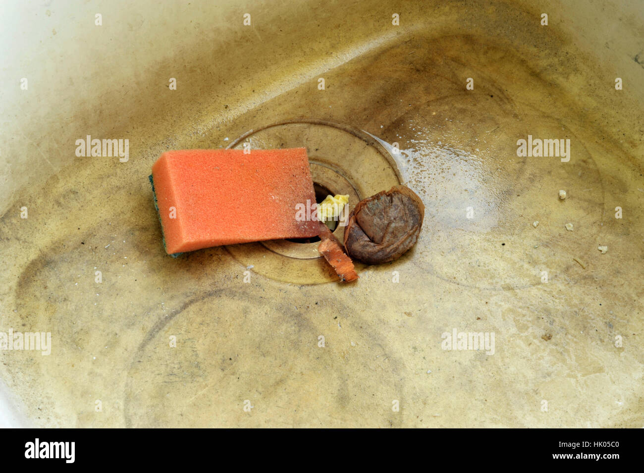 Stained and dirty unhygienic kitchen sink with wash sponge, food waste ...