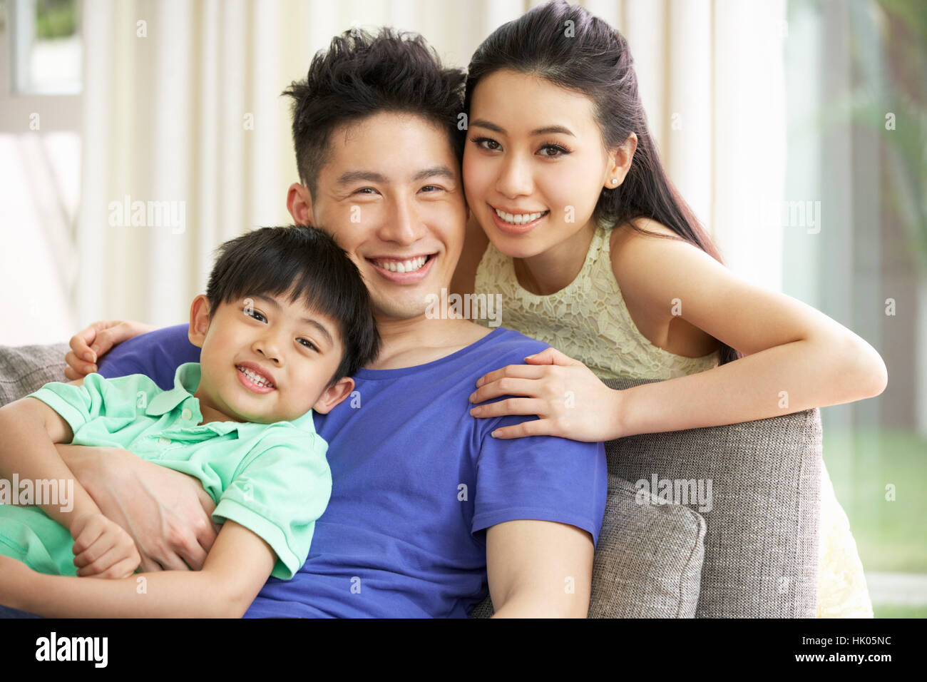 Chinese Family Sitting And Relaxing On Sofa Together At Home Stock ...