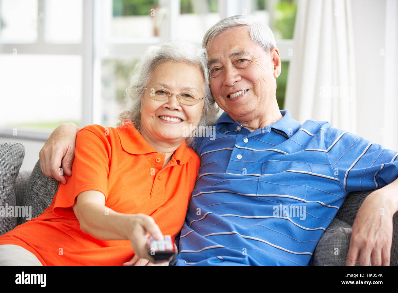Senior Chinese Couple Watching TV On Sofa At Home Stock Photo - Alamy
