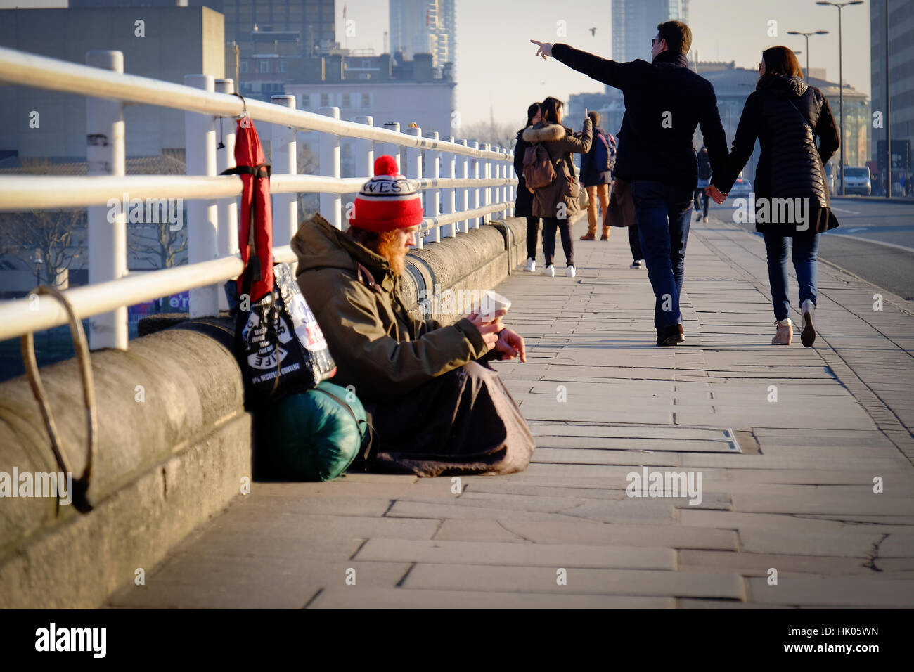 Tourists point out London landmarks whilst ignoring homeless man Stock ...