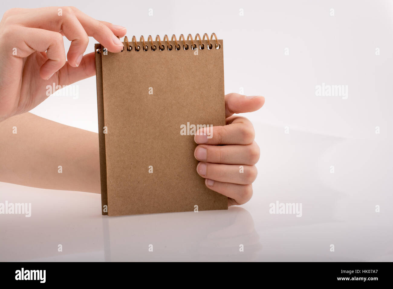 Hand holding brown color notebook on a white background Stock Photo - Alamy