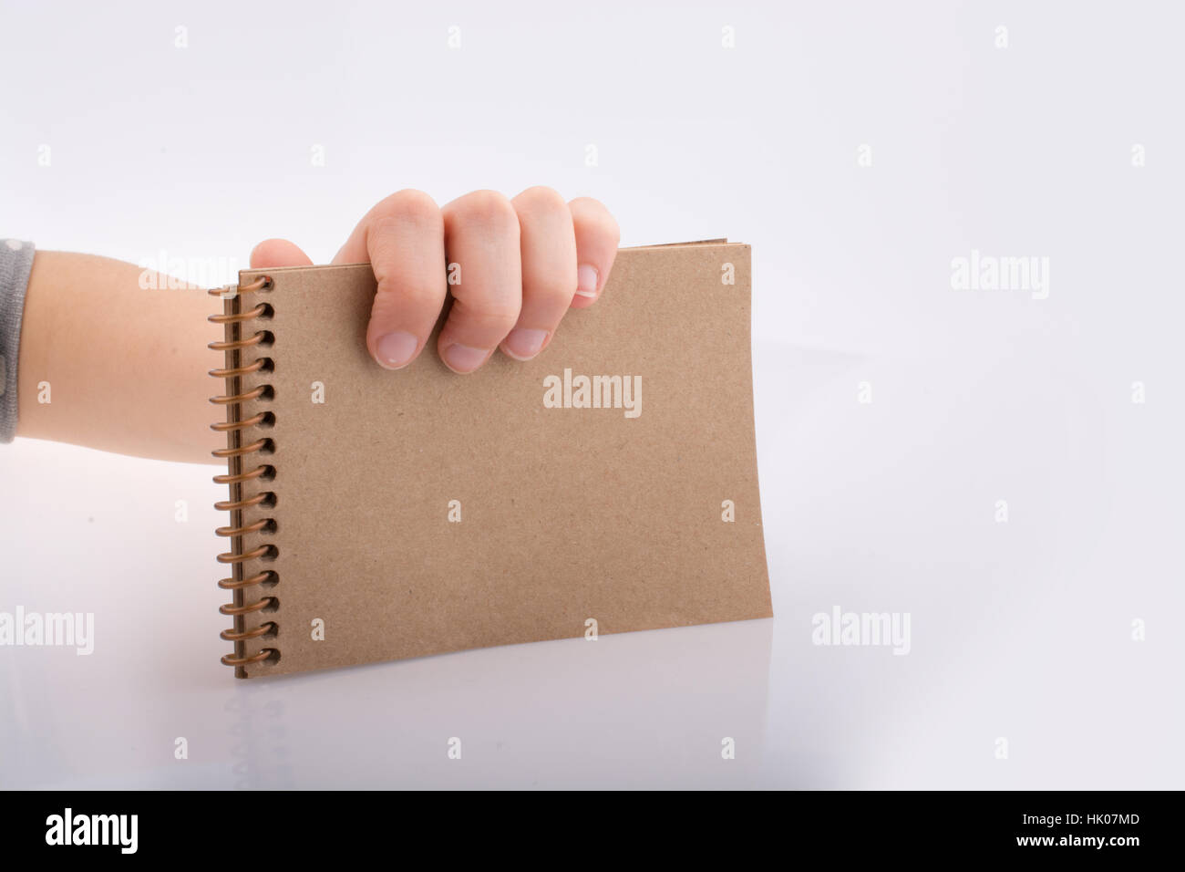 Hand holding brown color notebook on a white background Stock Photo - Alamy