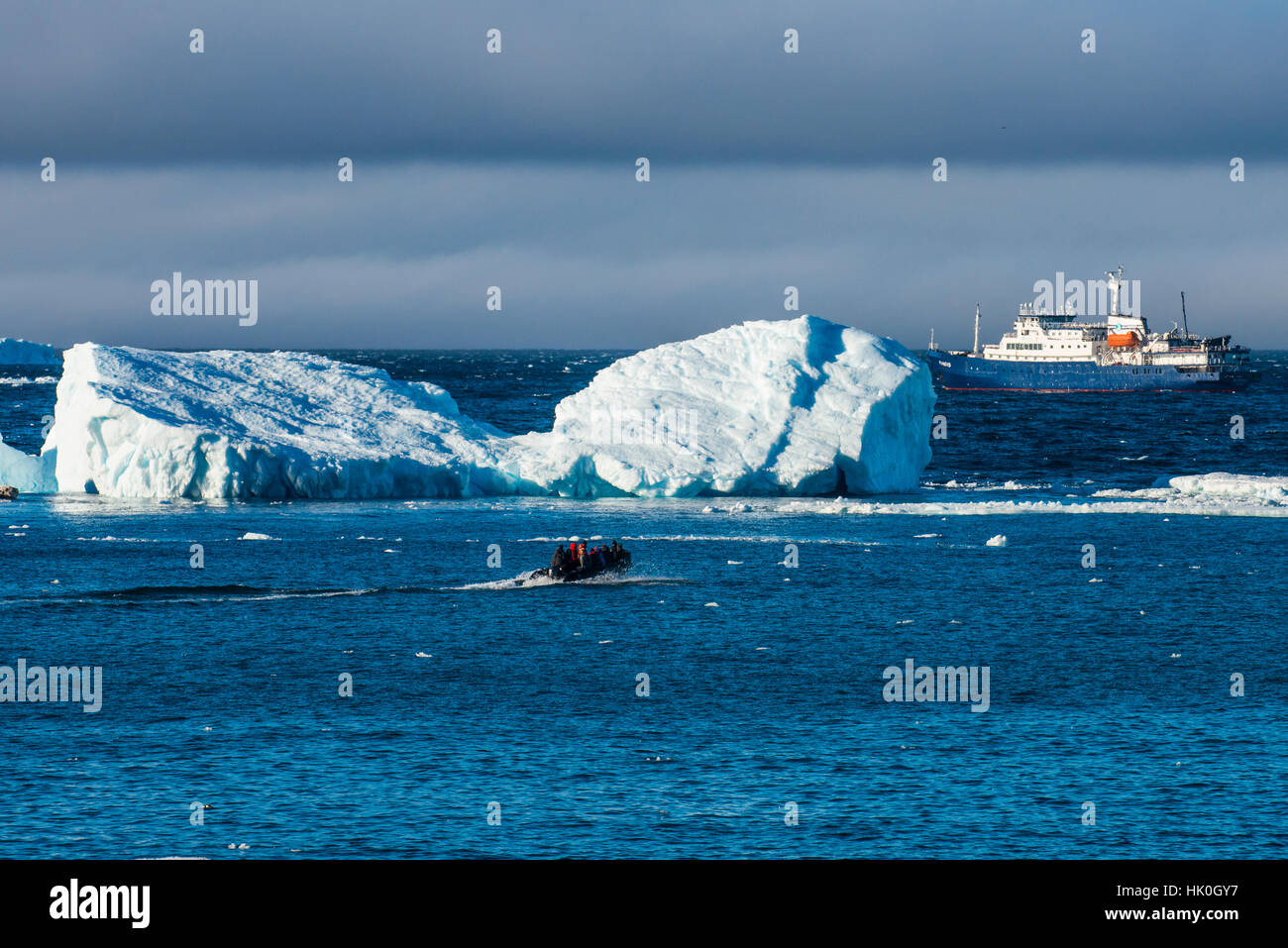 Zodiac cruising back to a cruise ship anchoring behind an iceberg ...