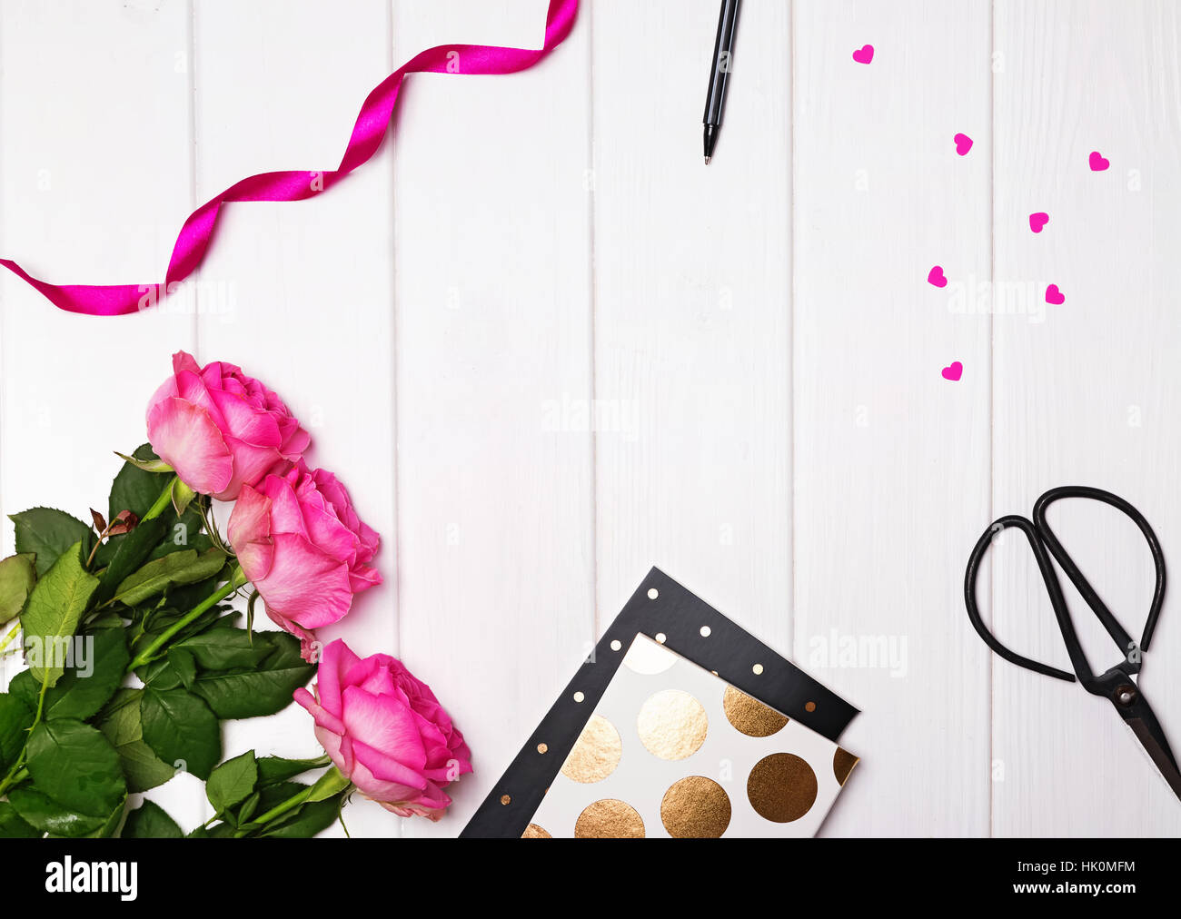 Pink roses, ribbon, notepads with gold dots, paper hearts and othe ...
