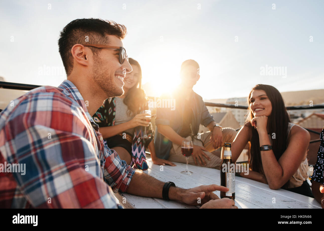 Handsome young guy having a rooftop party with best friends. Group of ...