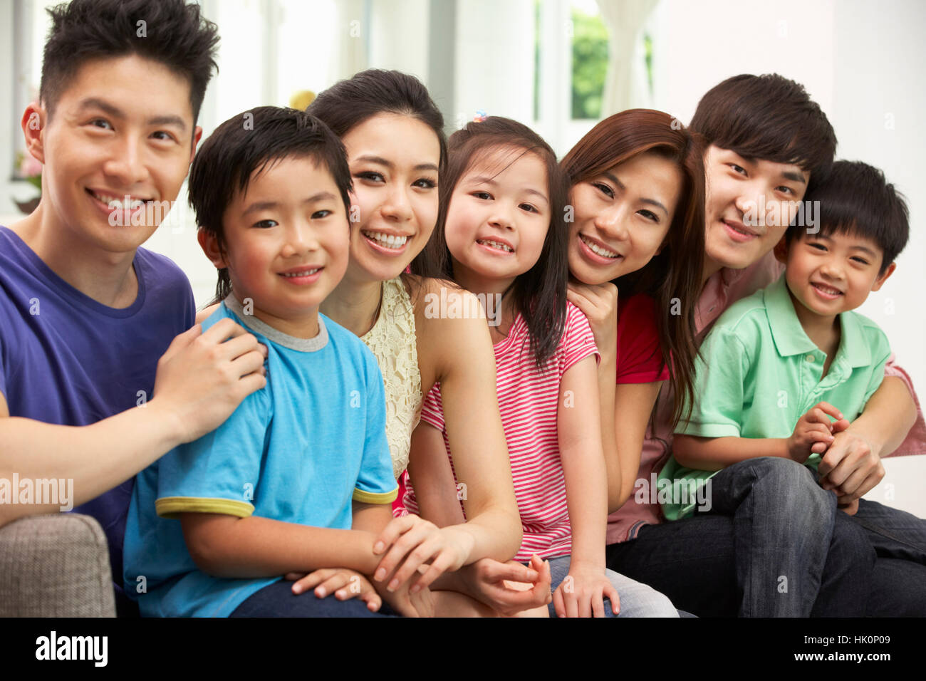 Two Chinese Families Sitting And Relaxing On Sofa Together At Home ...