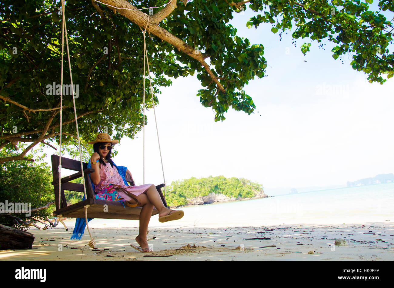 Thai woman sitting on the wooden swing bench with mauhom indigo natural ...