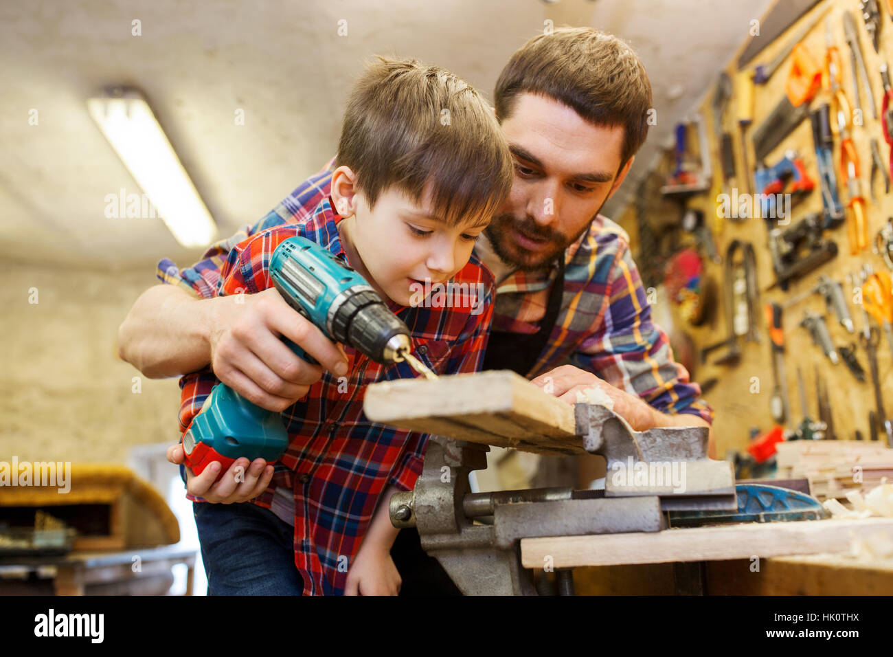 father and son with drill working at workshop Stock Photo - Alamy
