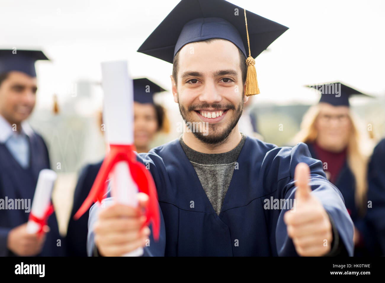 bachelor showing diploma and thumbs up Stock Photo - Alamy