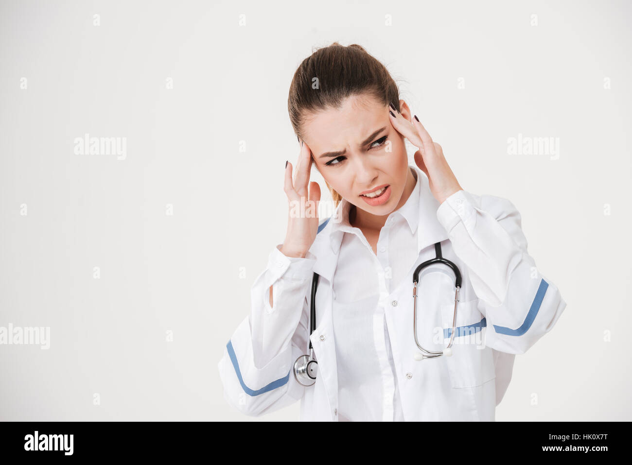 Sad stressed young woman doctor having headache over white background ...