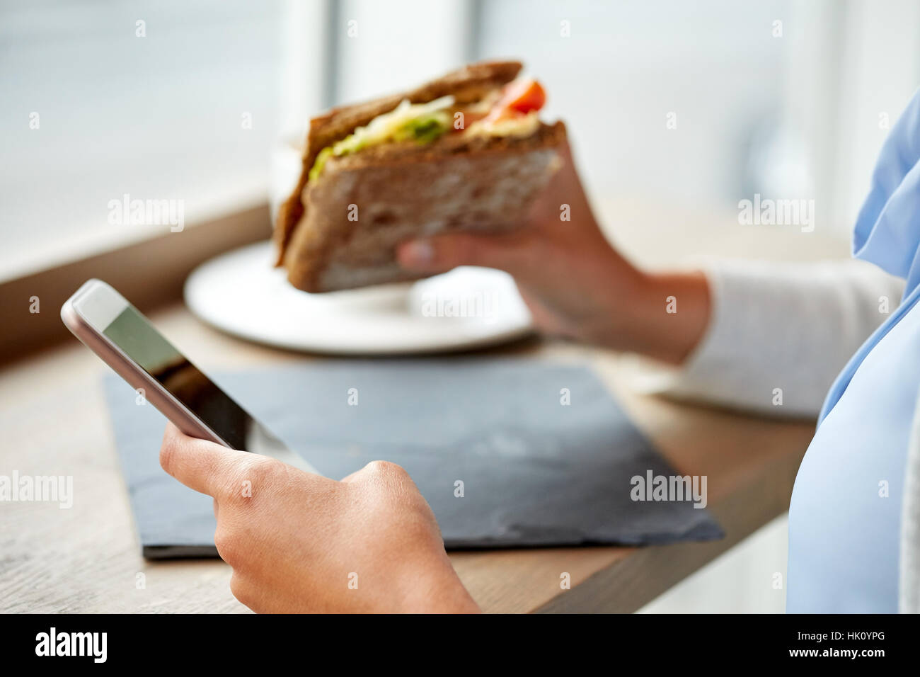 woman with smartphone and sandwich at restaurant Stock Photo - Alamy