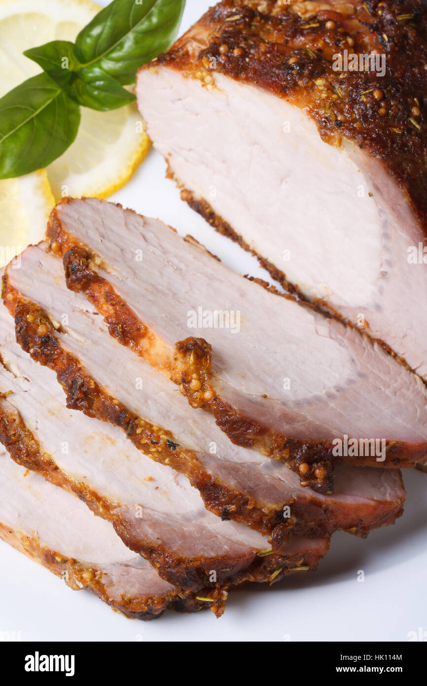 Tasty juicy baked pork fillet and basil on a white plate. vertical ...