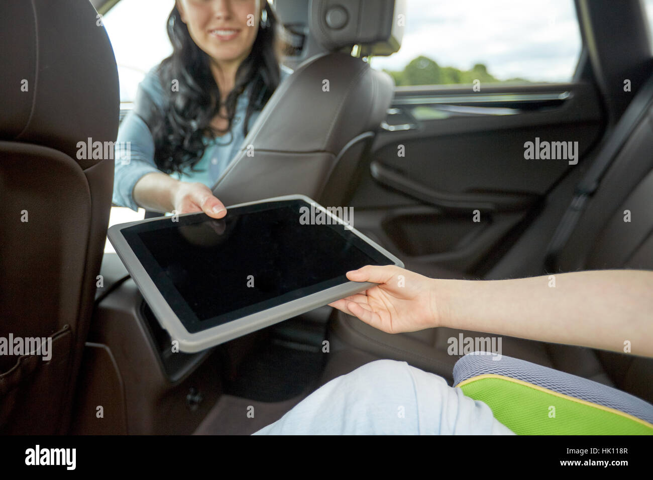 woman giving tablet pc to her child in car Stock Photo - Alamy