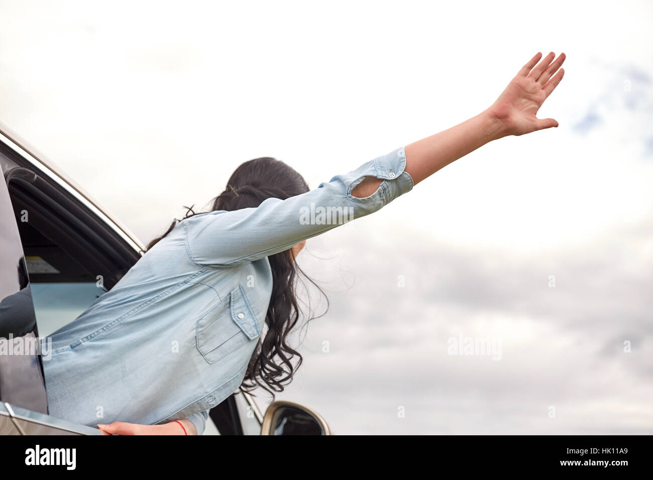 happy woman waving hand leaning out of car window Stock Photo - Alamy