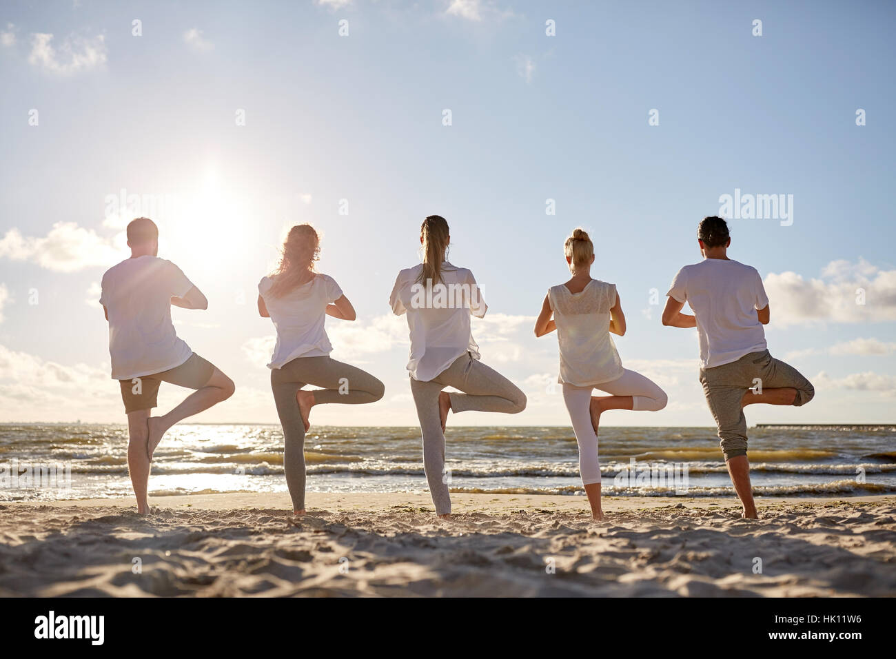 group of people making yoga in tree pose on beach Stock Photo - Alamy