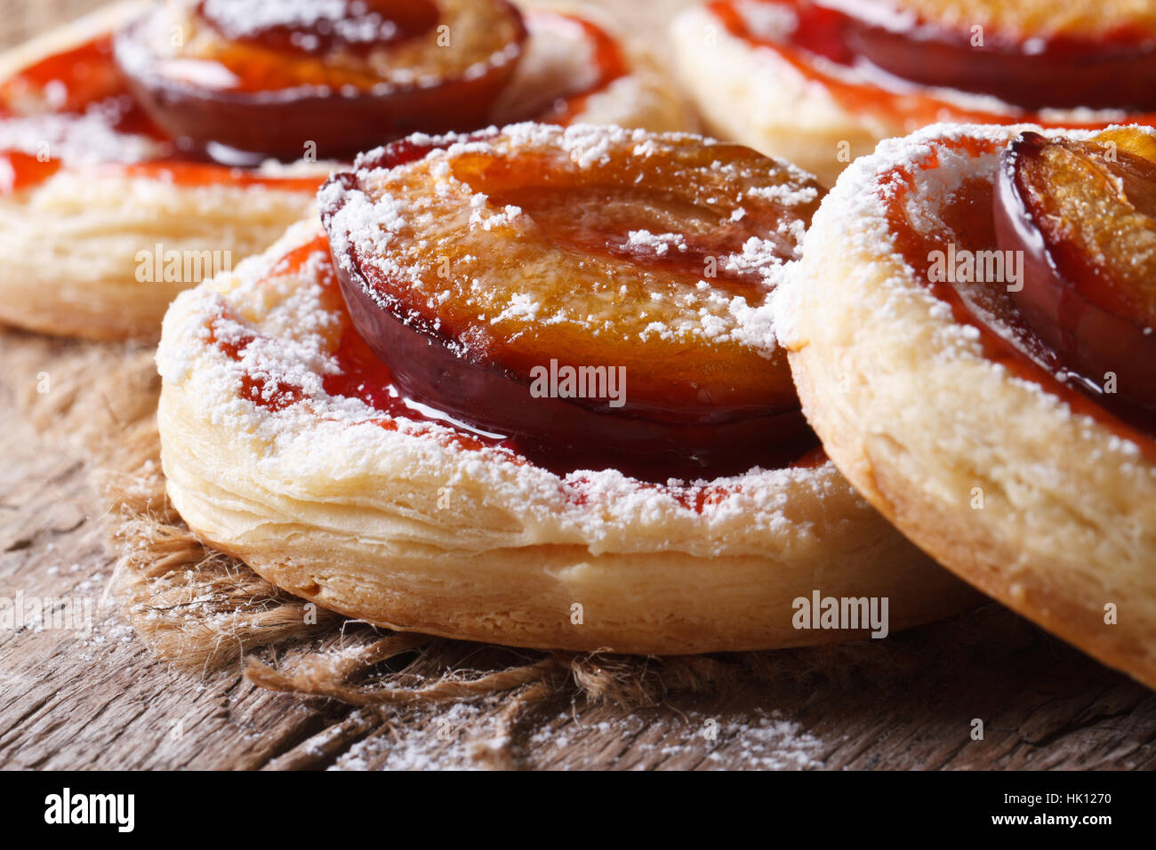 Cakes of puff pastry with plums macro on an old table. horizontal Stock ...