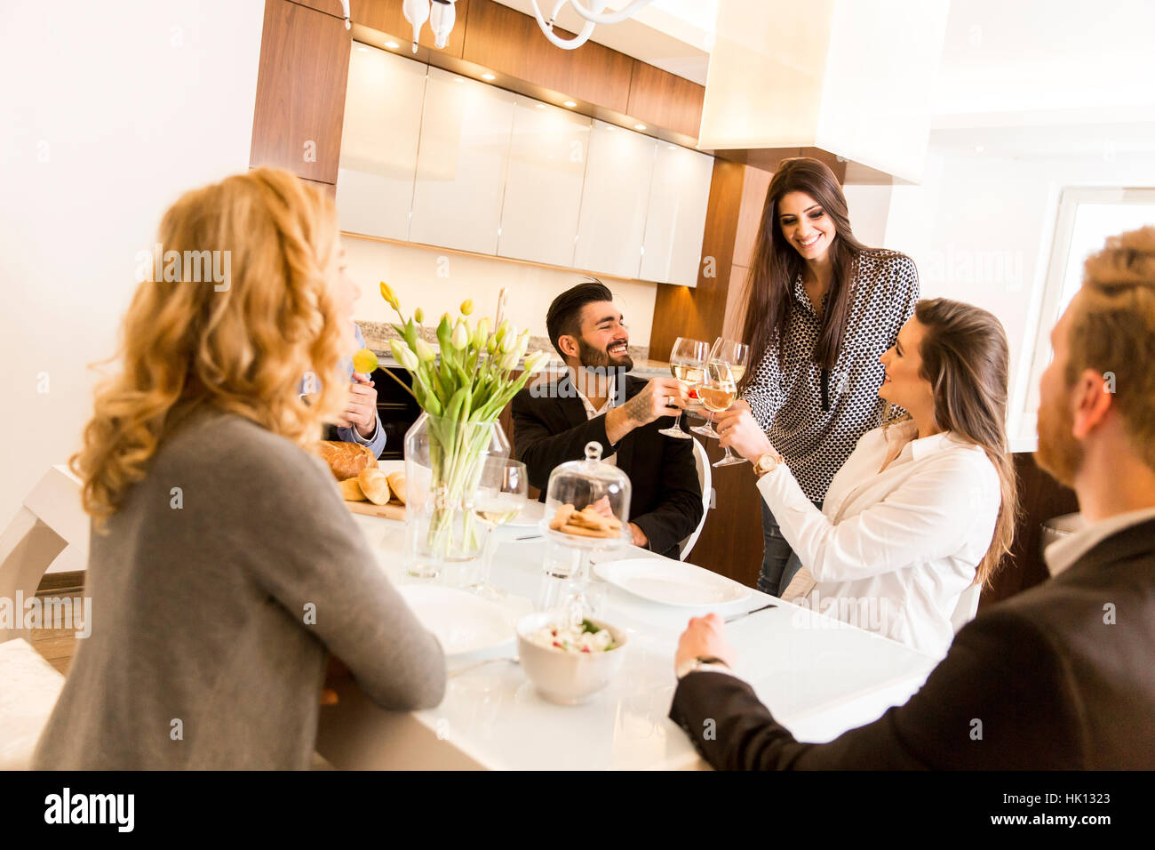 Friends interacting while having a meal at dining table and toast with ...