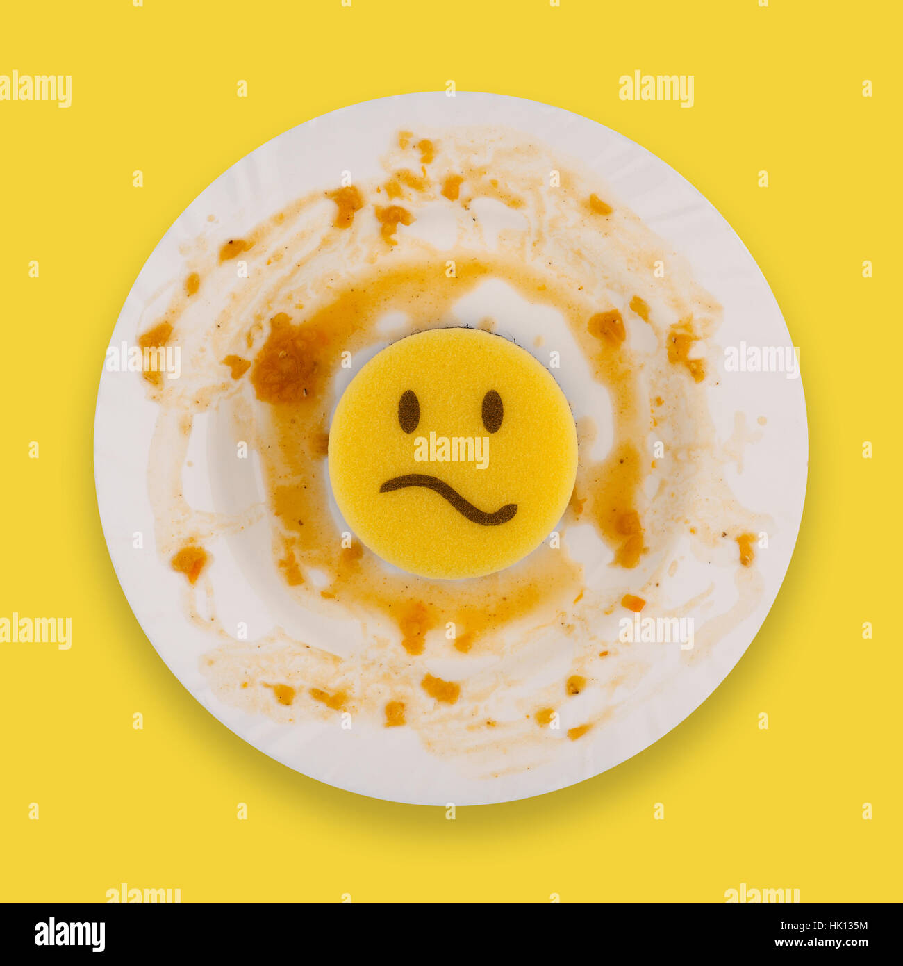 top view dish washing concept yellow sponge with sad face on a dining ...