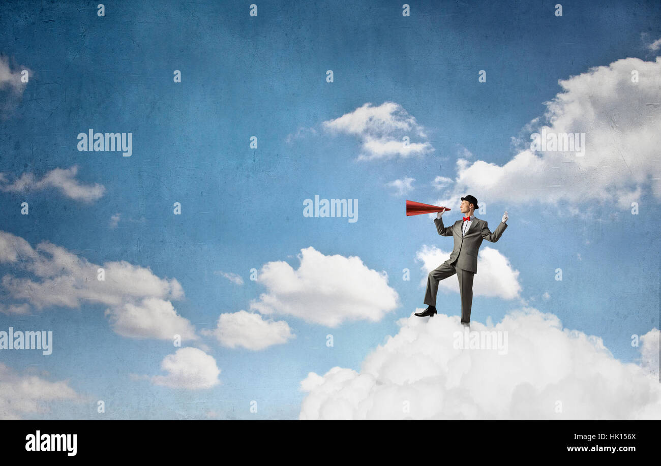 Young businessman on cloud screaming emotionally in paper trumpet hi ...