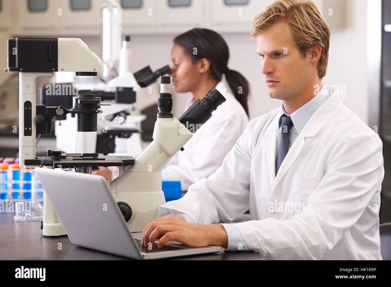 Male And Female Scientists Using Microscopes In Laboratory Stock Photo ...