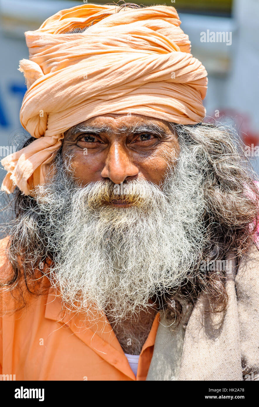 Close-up portrait of an elderly Indian man (Sadhu) in a vibrant orange ...