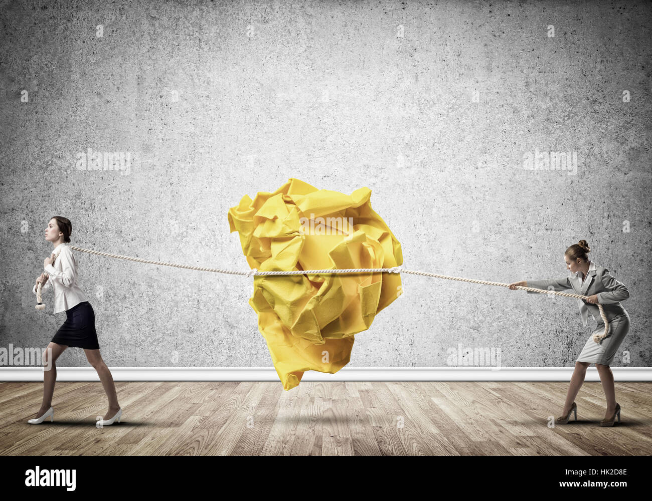 Two women pulling with effort big crumpled ball of paper as creativity ...