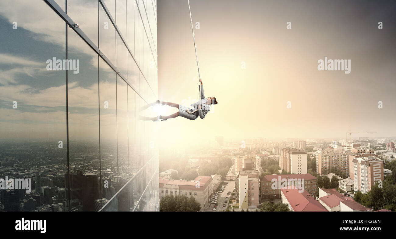Determined businesswoman climbing building with help of rope hi-res ...