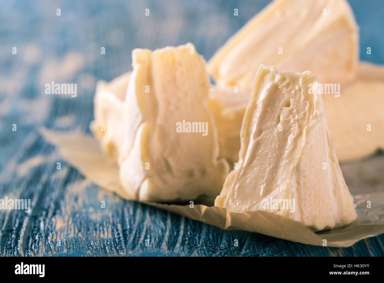 Horizontal photo of several portions of camembert. Cheese is cut to ...