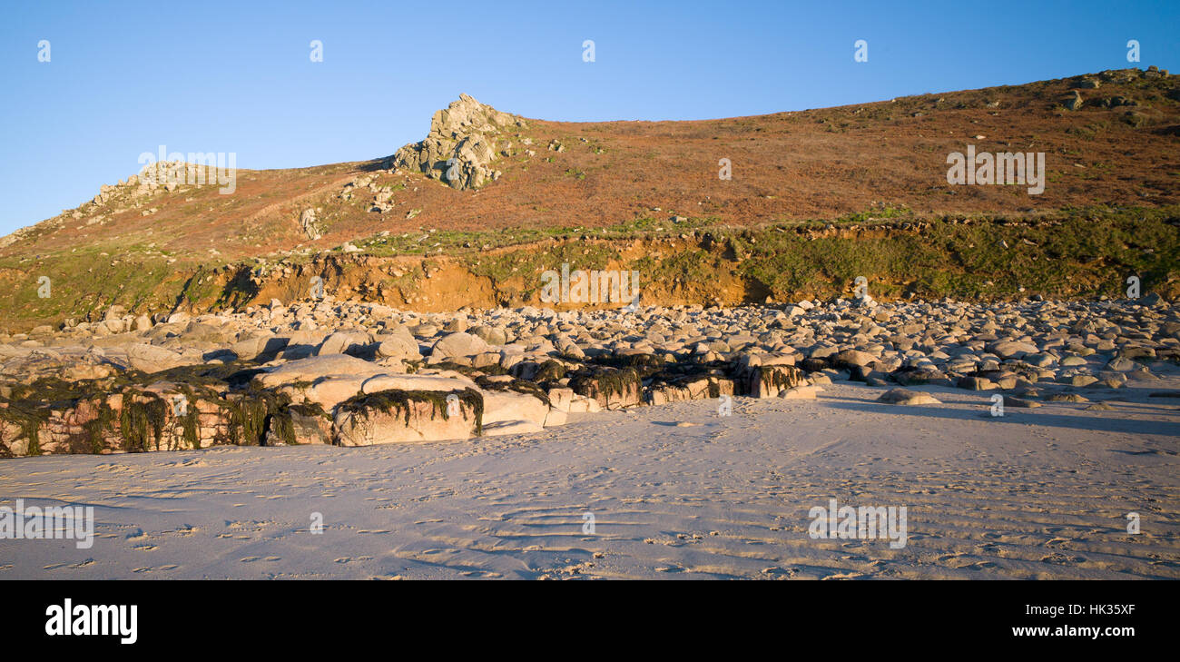 Granite cliffs, dikes, and boulders above sandy beach, Sennen Cove ...