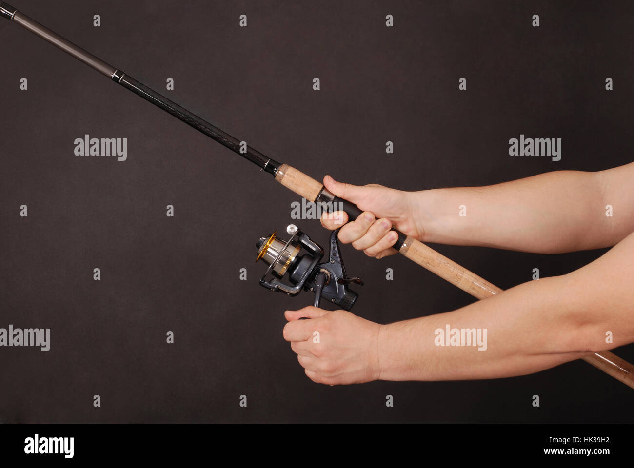 Man's hand holding a fishing rod on a black background Stock Photo - Alamy